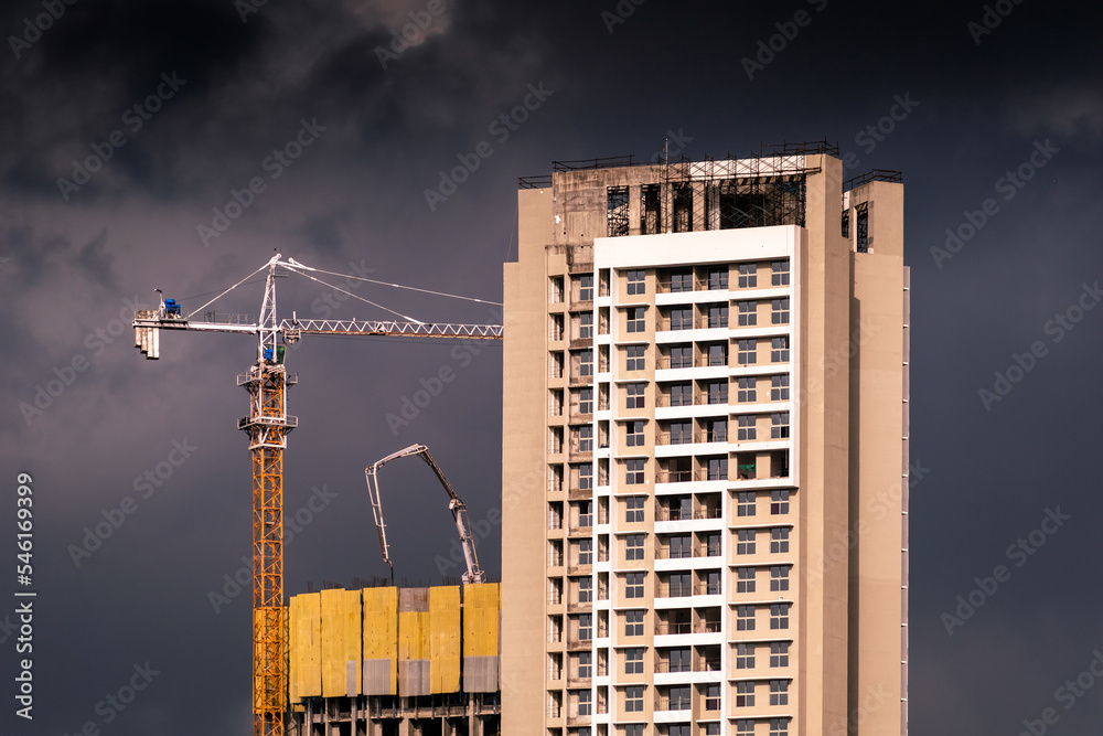 Construction cranes on top of a high rise skyscraper under construction ...