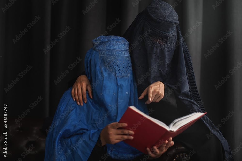 Afghan Muslim women with burka traditional costume, reading holy Quran ...