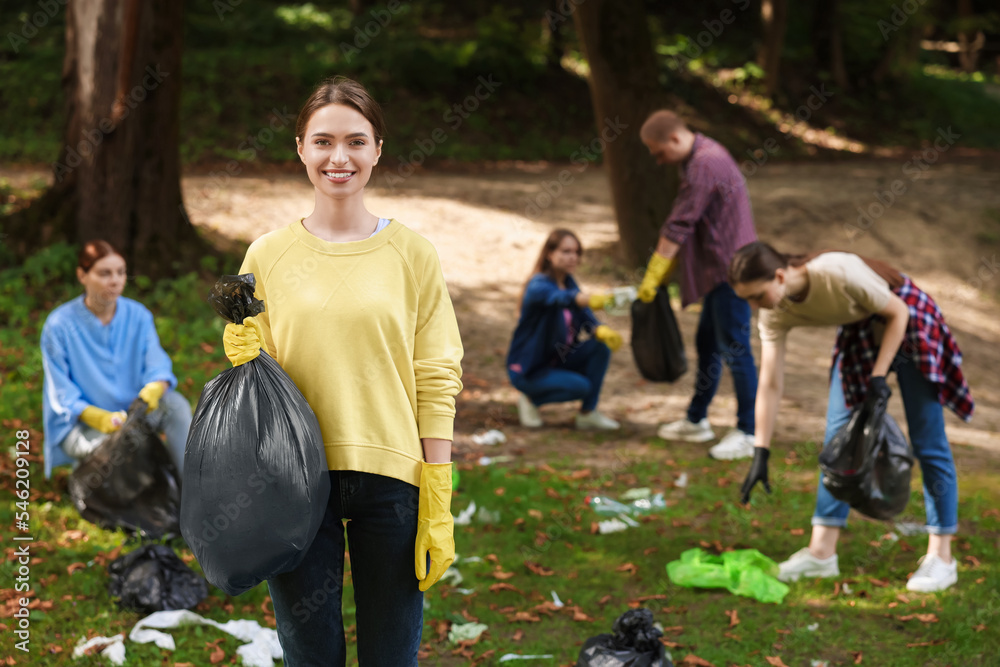 Young woman with plastic bag and group of people collecting garbage in ...
