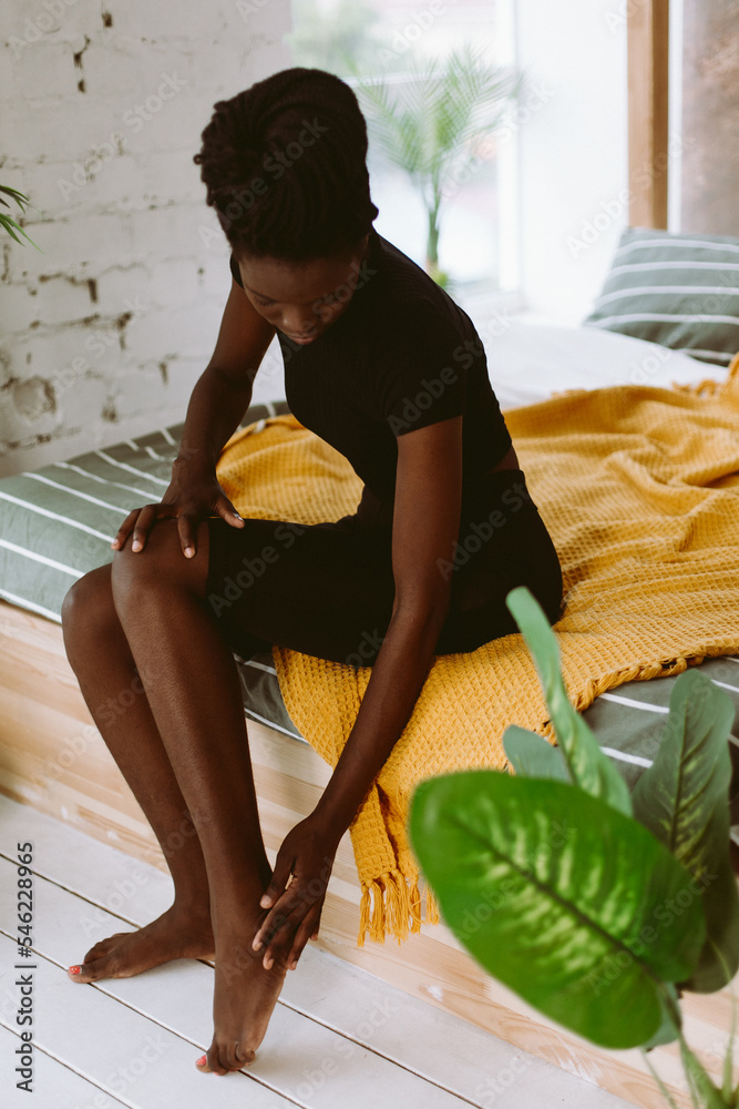 Beautiful afro american woman sitting on bed in decorated studio and ...