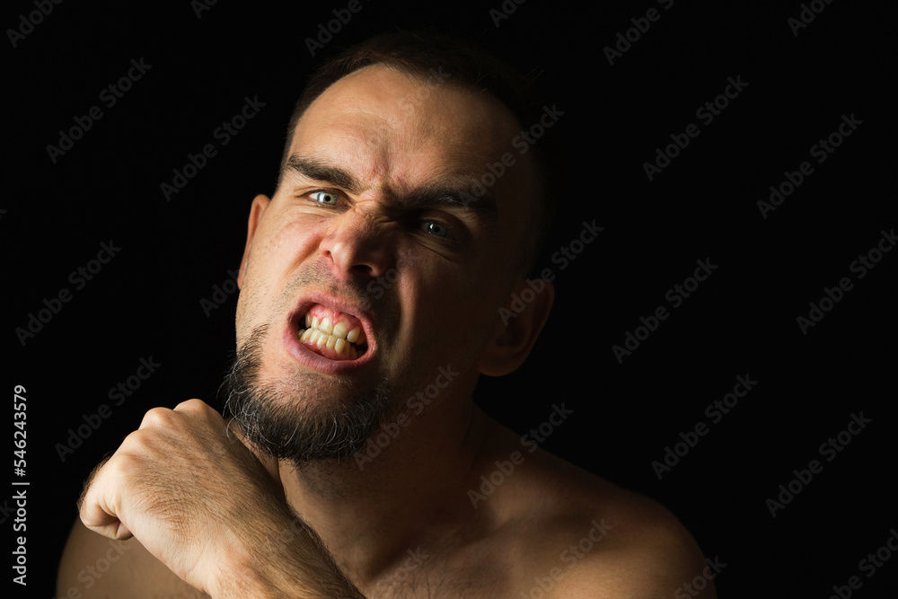 Shirtless bearded man, threatening with his thumb at his throat ...