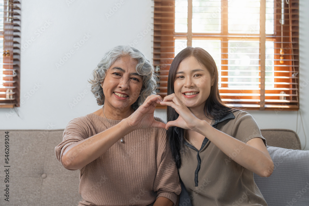 Foto de Loving adult daughter hugging older mother on couch at home ...