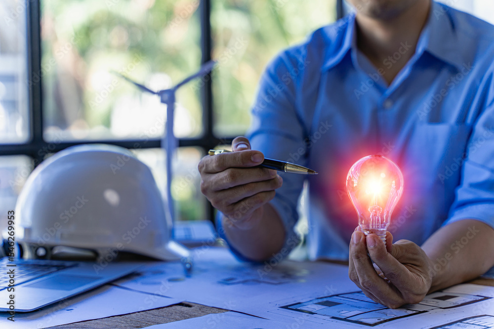 Energy engineer holding a light bulb while thinking innovative concept ...