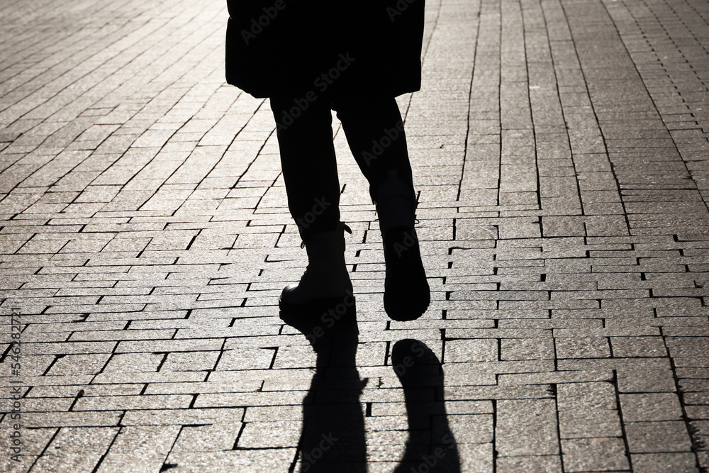 Black silhouette and shadow of lonely woman walking on a street. Female ...