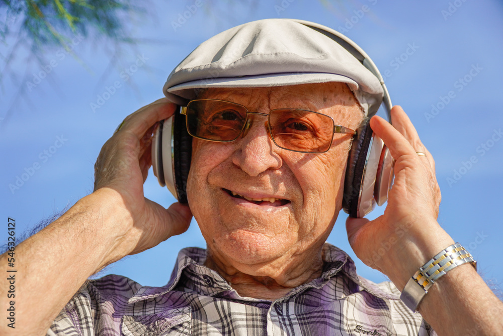 old man talking with a family with a headphone in a park. Elderly and ...