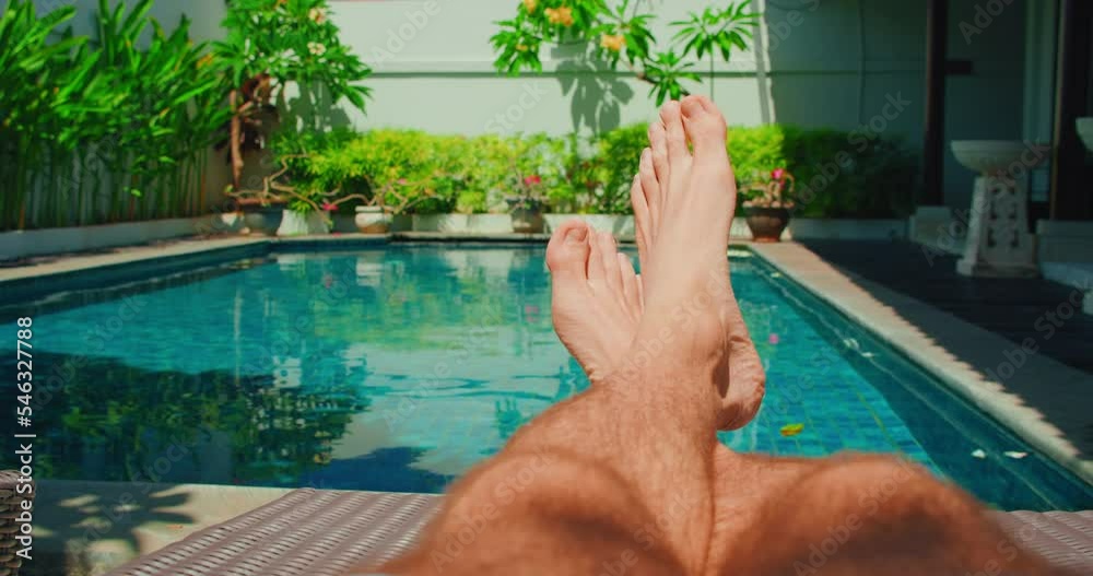 Vacation. Mans feet on the background of the swimming pool, relax on ...