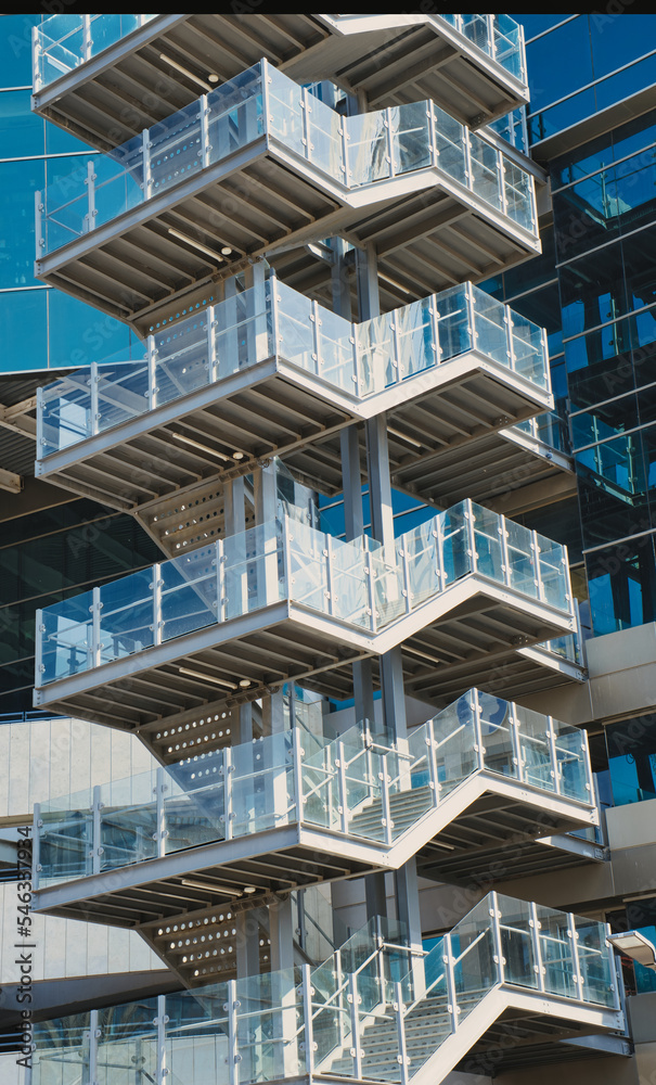 Multi-story exterior staircase with glass railings in front of a modern ...