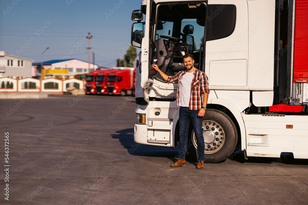 smiling handsome masculine driver stranding next to his white truck ...