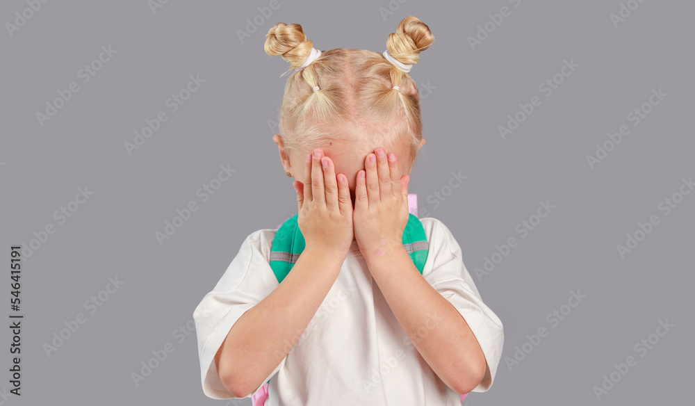 The little girl covered her face with her hands, the child holds both ...