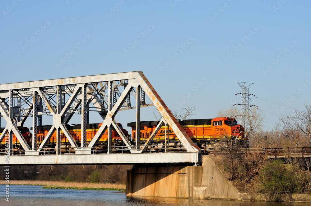 Multiple locomotive units lead a freight train through a bridge over ...