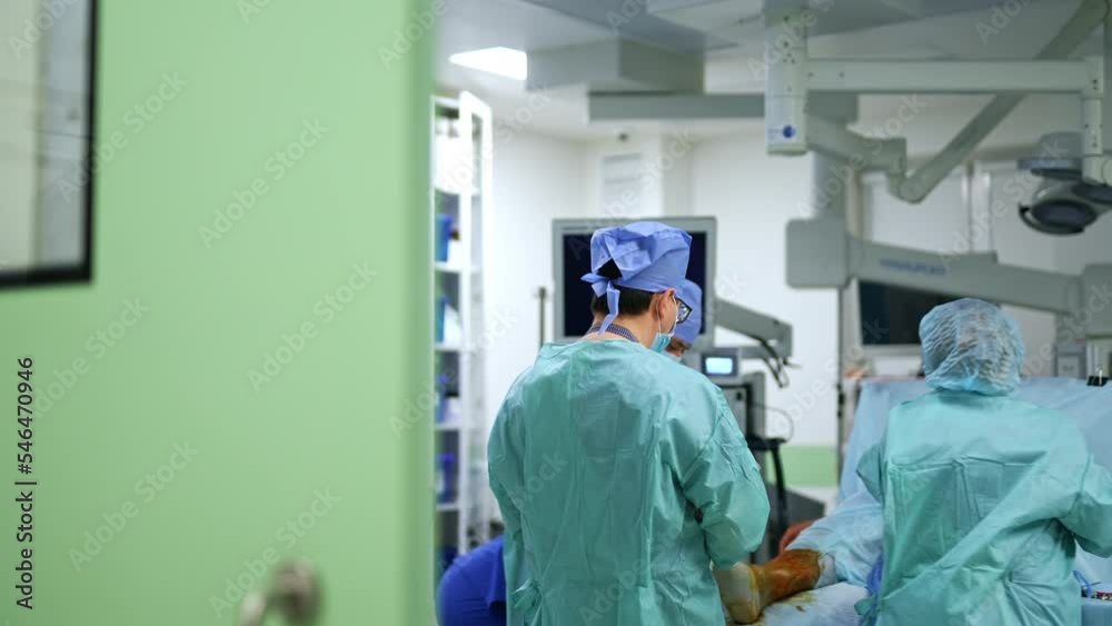 Adult male doctor wearing device glasses looking down at the operated ...