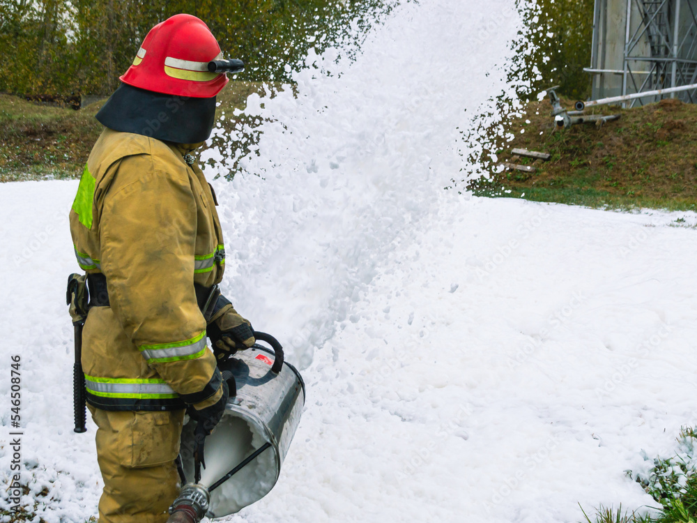 A firefighter in protective clothing extinguishes the fire by feeding ...