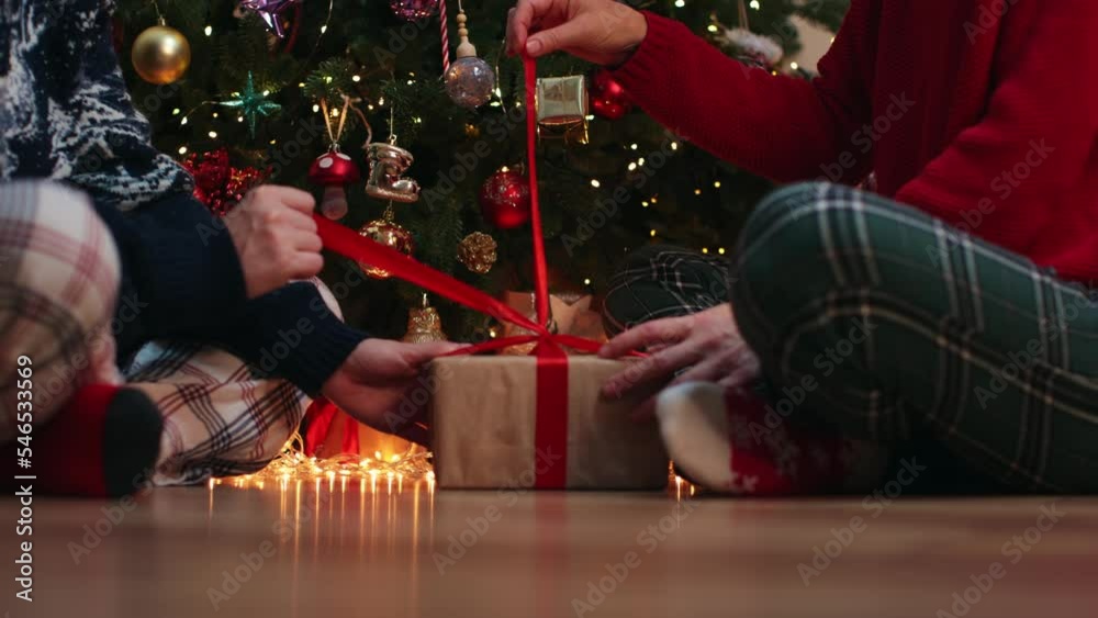 two female hands untie bow on Christmas gift box together. female ...