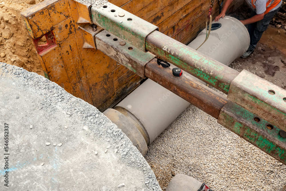 Builder installing big diameter concrete drainage pipe protected by ...