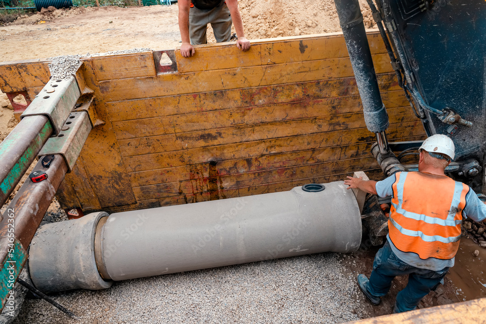 Builder installing big diameter concrete drainage pipe protected by ...