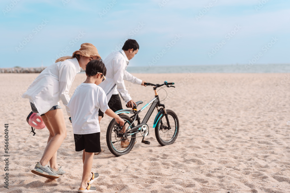 Family on the beach they are enjoy bicycle. Happy father, mother and ...