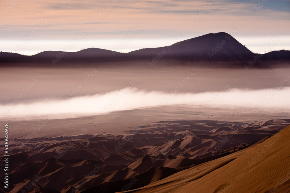 Sand dunes with clouds and layers of fog. Stock Photo | Adobe Stock