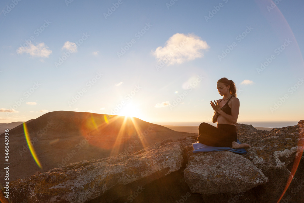 Girl doing yoga lotus position on the top of a volcano at sunset in ...