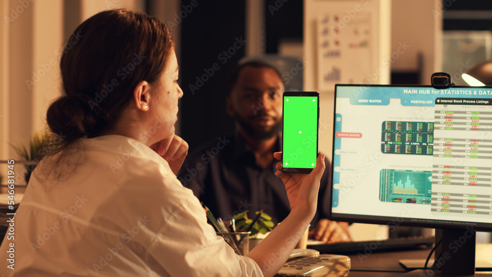 Employee holding greenscreen template on smartphone and working with ...