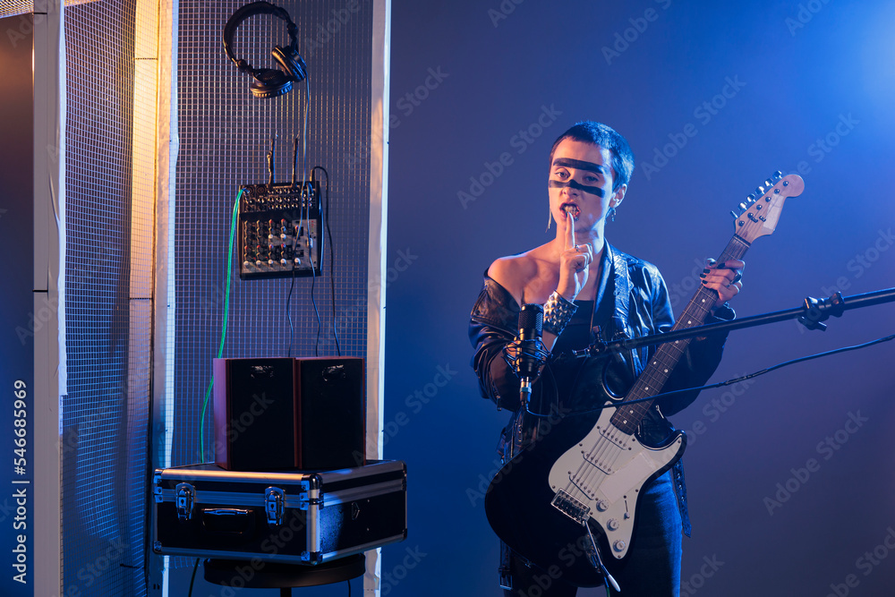 Punk rock artist doing hush mute sign, playing guitar at microphone and ...