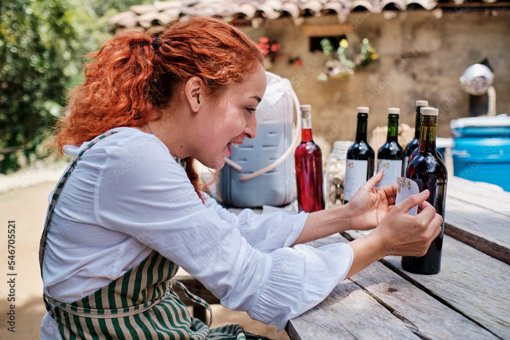Smile young woman labeling wine bottles Stock Photo | Adobe Stock