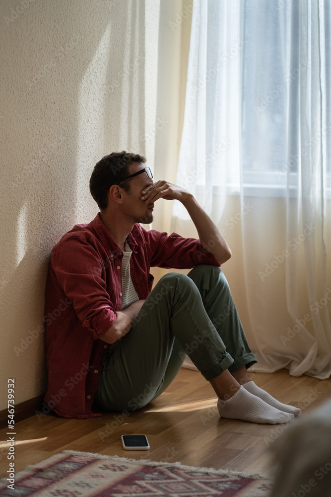 Upset depressed young man sitting with closed eyes on floor at home ...