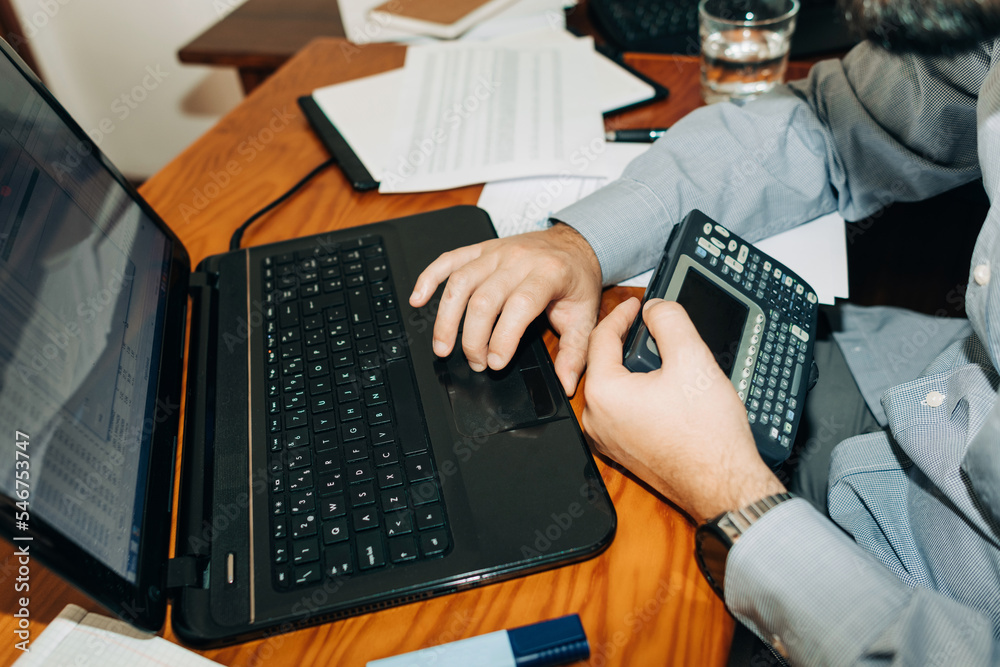 Man using scientific calculator and laptop Stock Photo | Adobe Stock