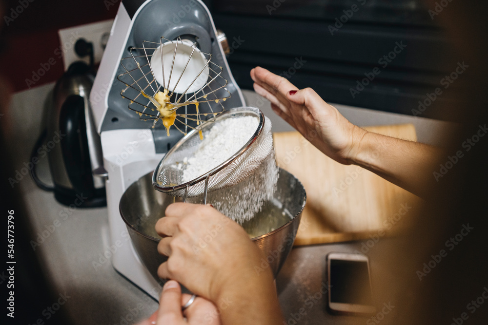 Mother and daughter adding flour in bowl Stock Photo | Adobe Stock