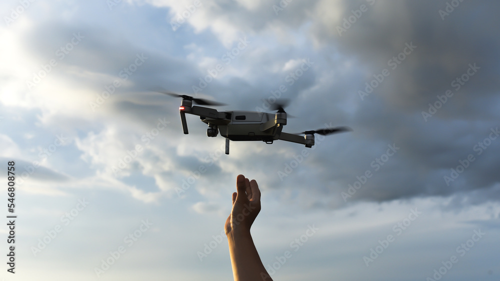 Hand reaching for drone outdoors at sunrise. Testing an aerial unmanned ...