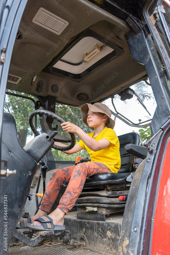 Boy driving a tractor. Boy sitting behind the wheel of a tractor. Stock ...