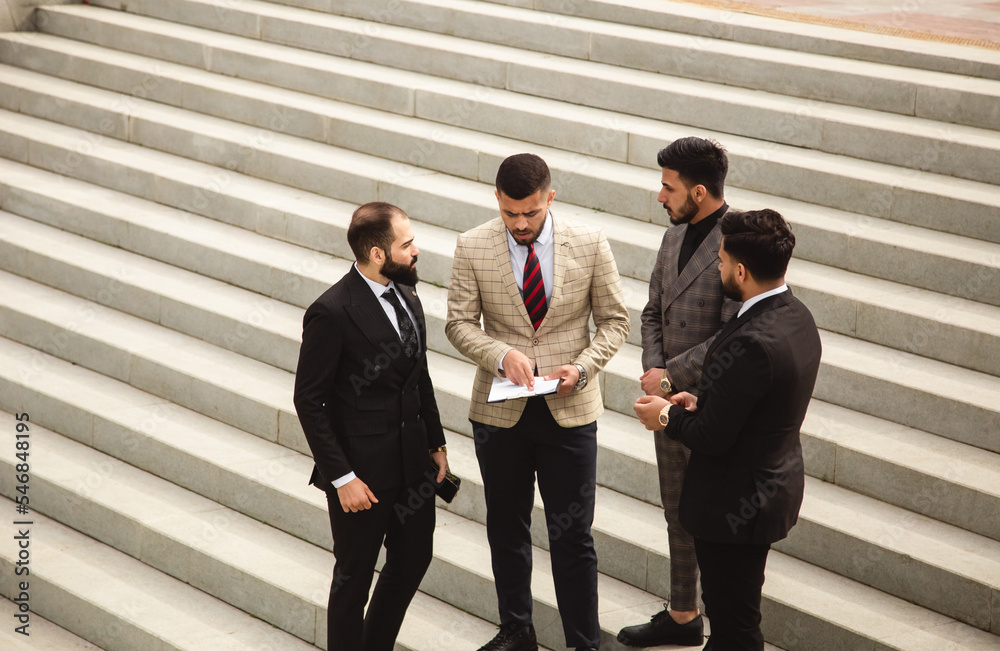 Business people outdoor meeting. A group of men in suits stands against ...