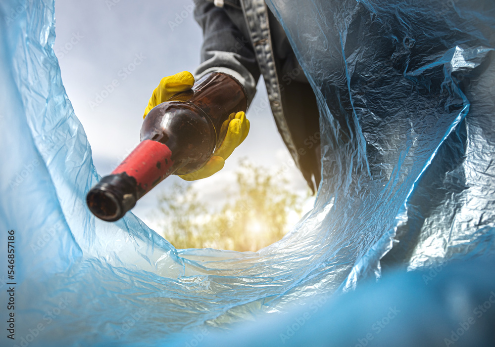Close-up of a hand throwing garbage into a plastic bag. View from ...