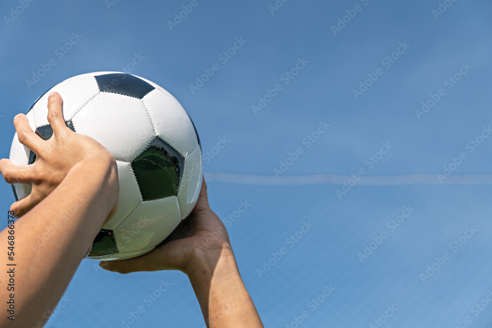 Athlete standing with ball on football field during sunrise, soccer ...