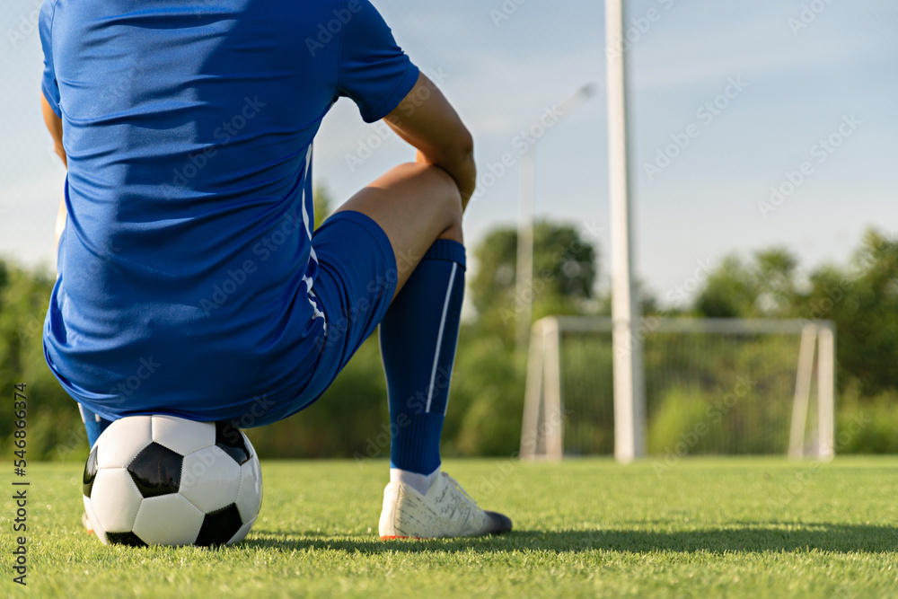 Athlete standing with ball on football field during sunrise, soccer ...
