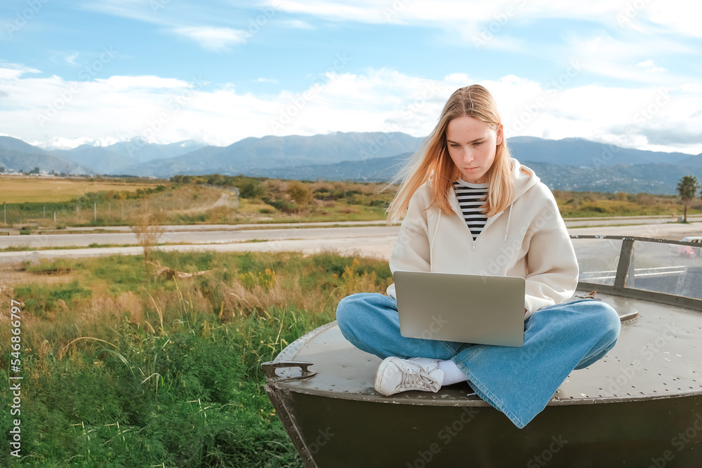 Remote work.Girl freelancer works remotely on the sea shore. workation ...