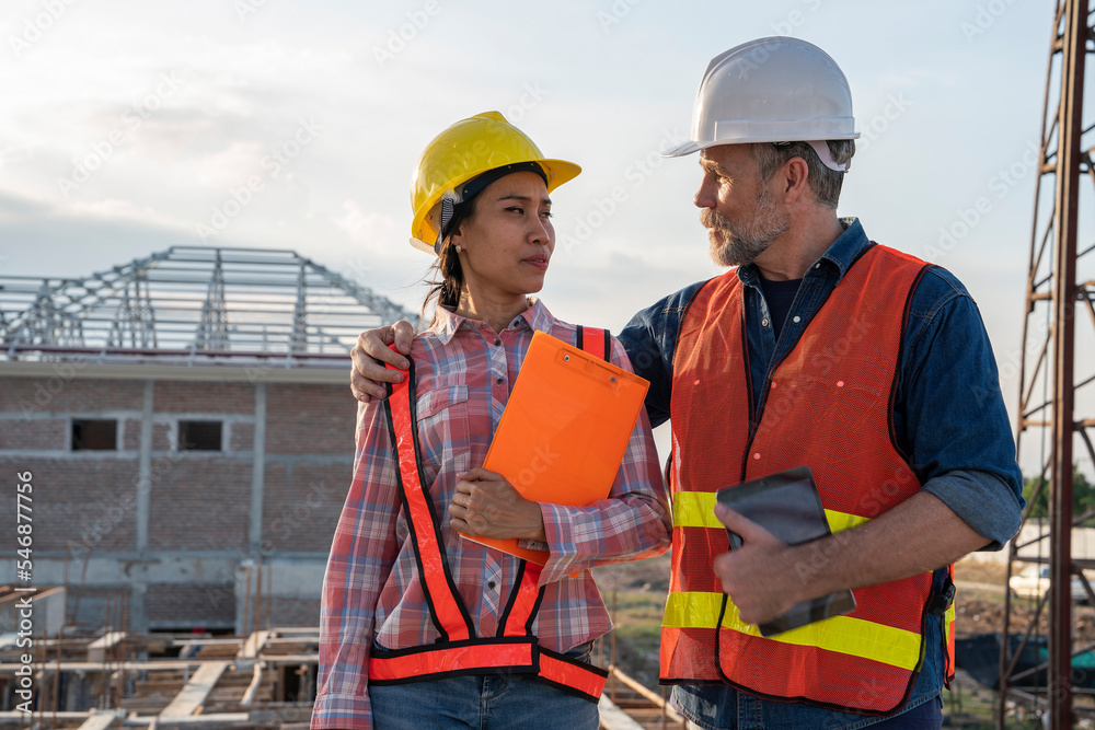 Middle-aged male contractor encouraging uniformed Asian female worker ...