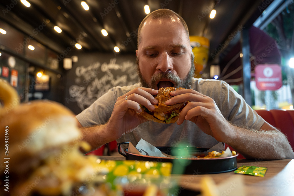 Caucasian bearded middle-aged man with an appetite eating burger and ...