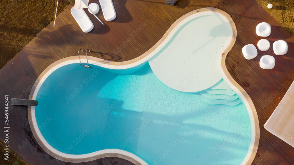 Aerial view of a swimming pool with wavy and curved shapes. Around the ...