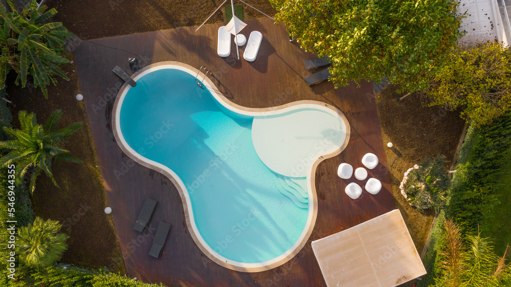 Aerial view of a swimming pool with wavy and curved shapes. Around the ...