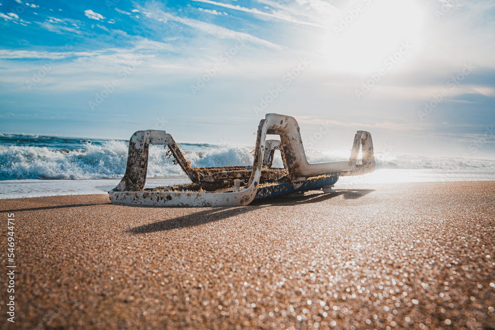 Washed up Plastic beach chair stuck in sand on shoreline during a ...