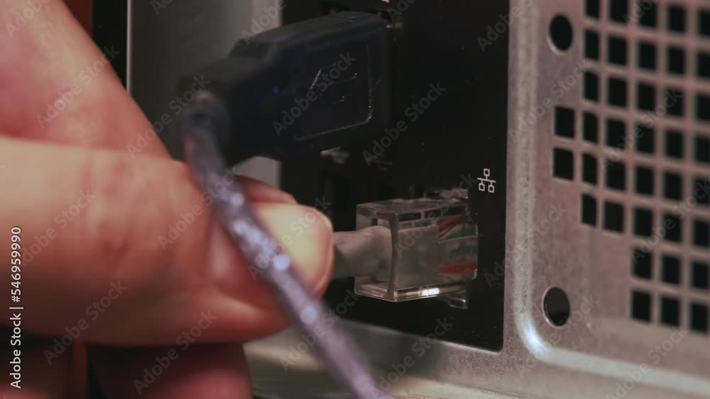 Close-up of a male hand inserting a network cable into a computer jack ...