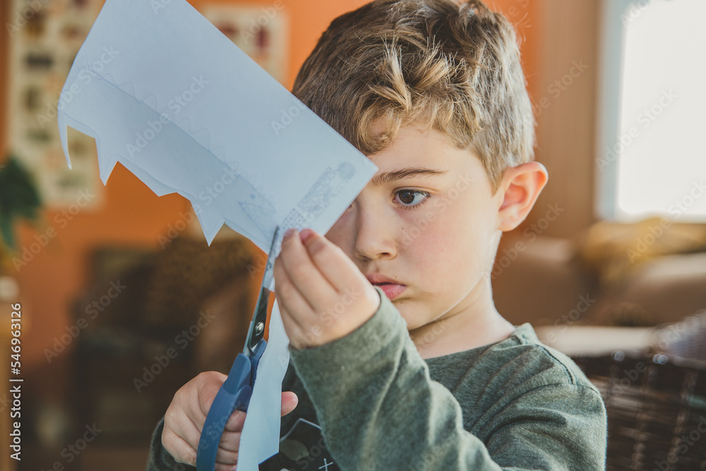 Menino concentrado recortando papel em trabalho escolar Stock Photo ...