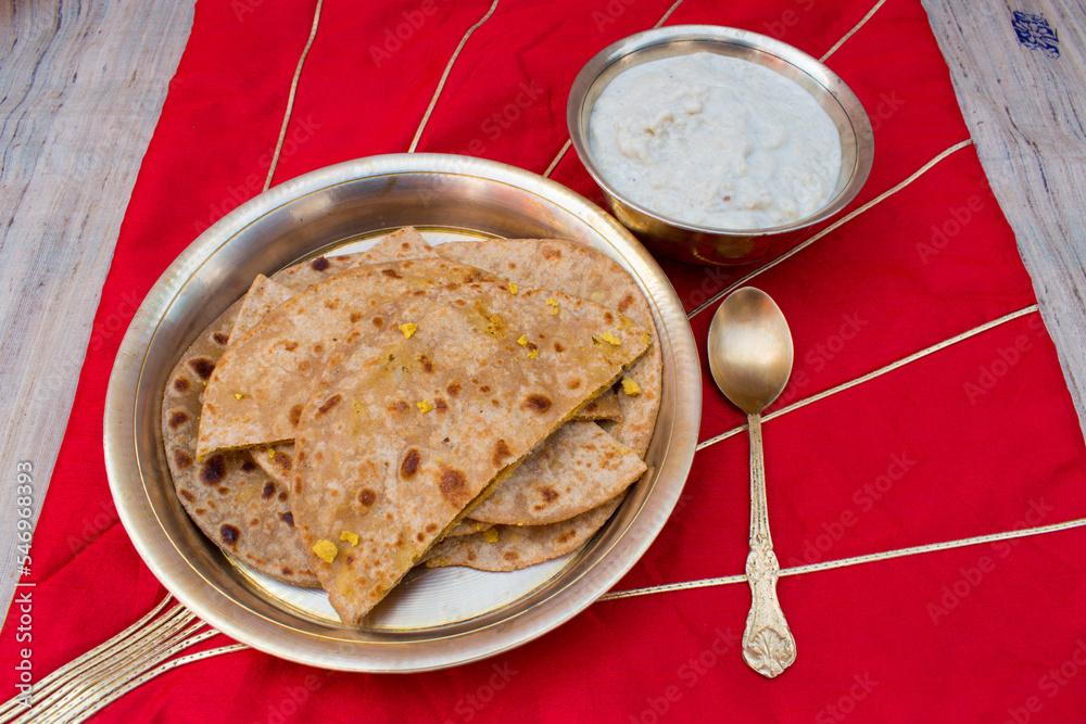 Dal Puri or dal stuffed paratha in brass plate and Gur kheer or kheer ...