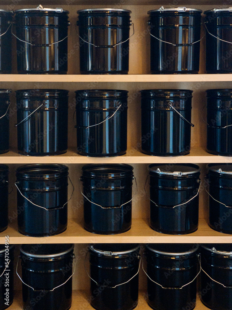 Wooden shelves with rows of black unlabeled containers, a storage ...
