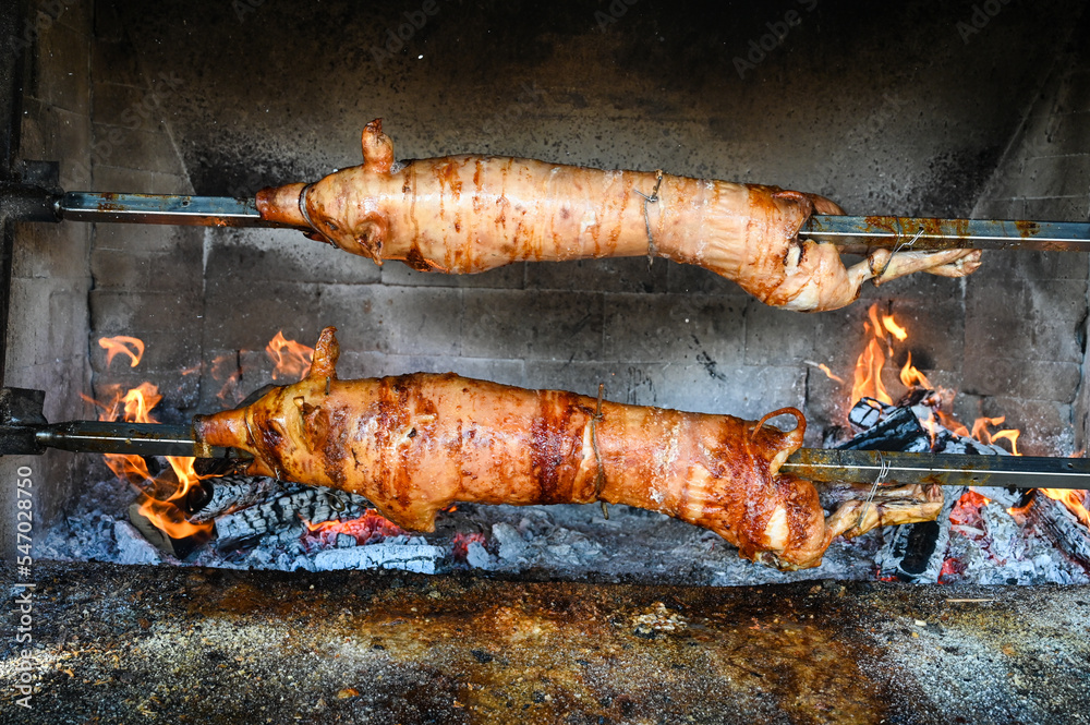 Roasted whole pigs on fire. Grilled pig on skewer. Roasting pig on a ...
