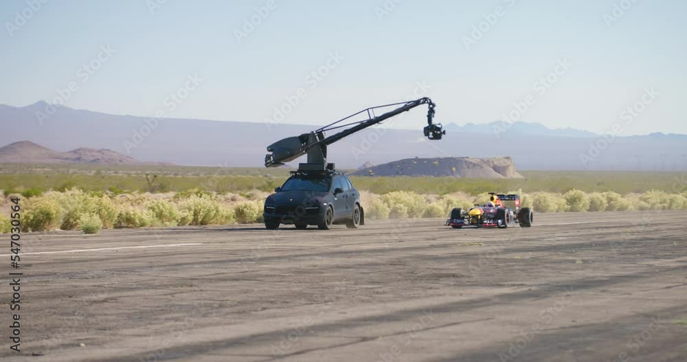 Arm car cinema camera follows and films Formula 1 car driving down an ...