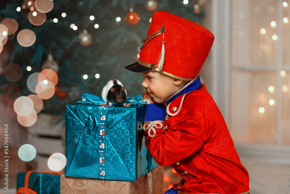 A boy in a nutcracker costume plays with the mouse symbol of the year ...