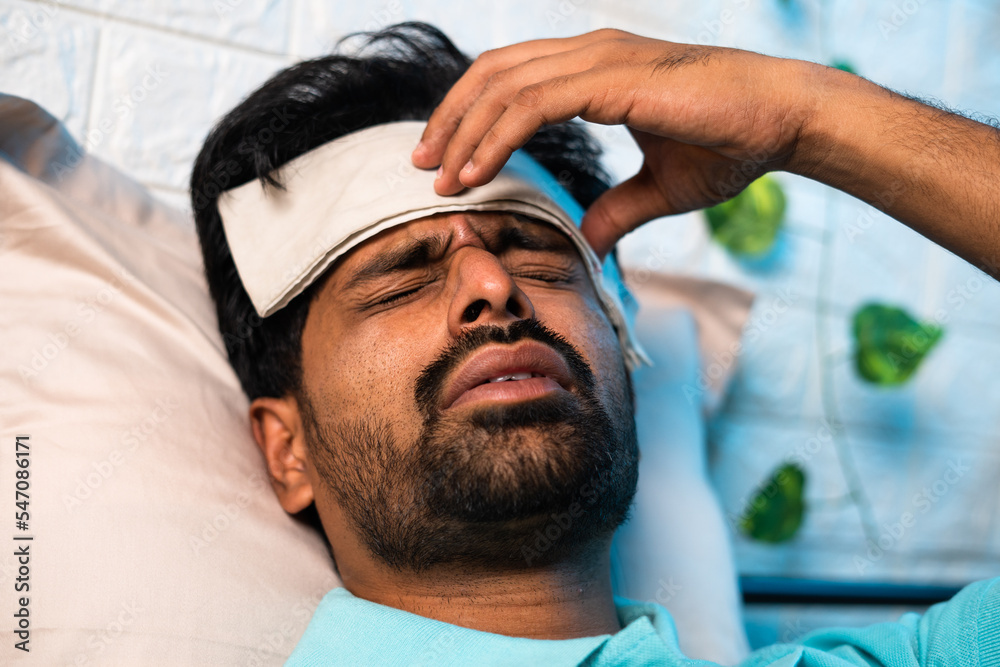 close up head shot of young indian sick man suffering from fever while ...