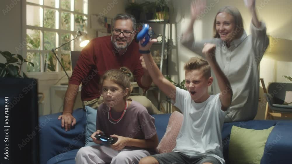 Teen kids playing video game on TV with excitement as parents cheering ...