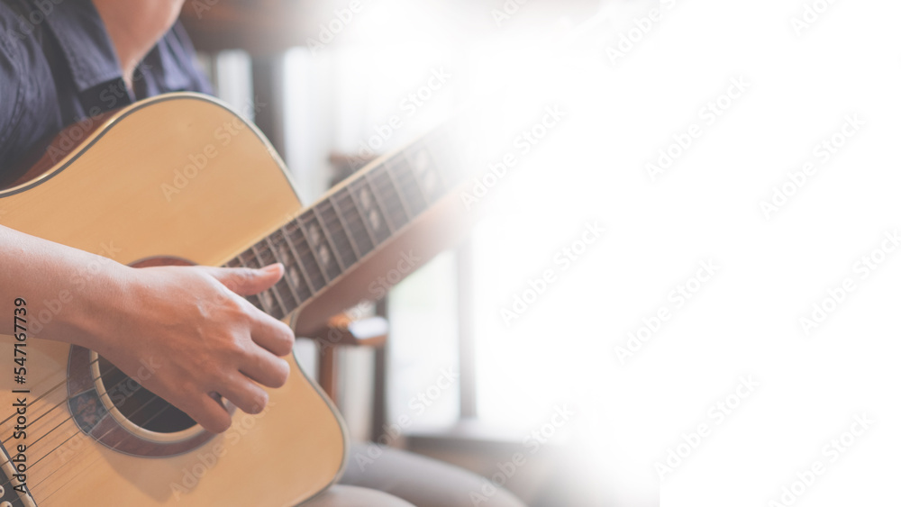 Musician is sitting and playing an acoustic guitar with white copyspace ...